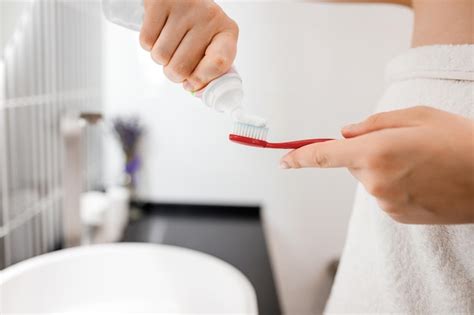 Premium Photo Woman Applying Toothpaste On Brush In Bathroom