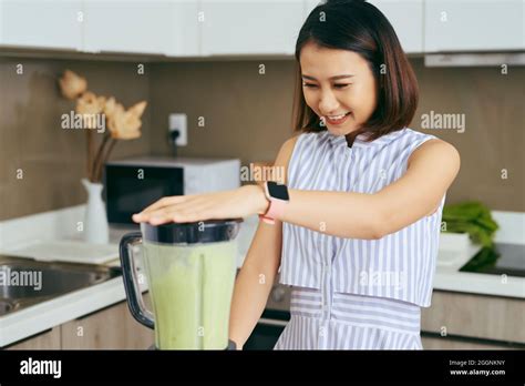 Pretty Young Asian Woman Making Smoothie In Blender In The Kitchen