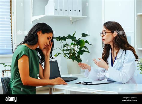 Young Female Doctor Explaining Treatment To Worried Woman Patient At