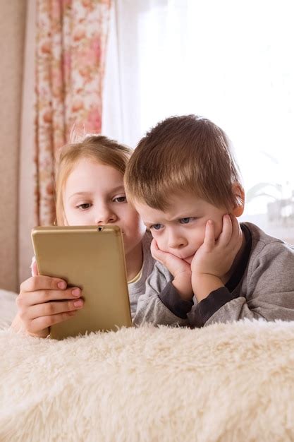 Les Enfants Sont Allongés Sur Le Lit En Regardant Des Dessins Animés