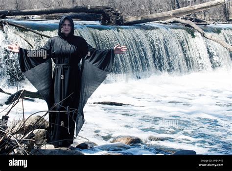 Hooded Woman In Black Robes In Front Of The Waterfall Witches