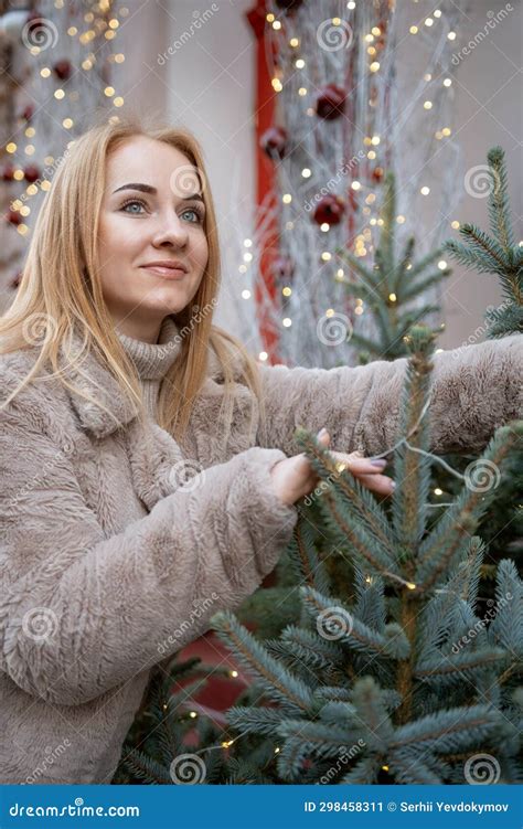 Attractive Young Woman Near The Christmas Tree Standing Outdoors