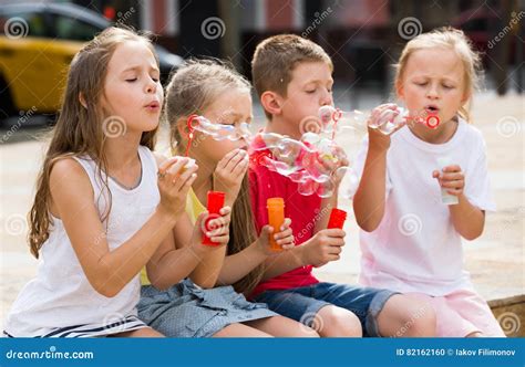 Quattro Bambini Positivi Che Soffiano Le Bolle Di Sapone Fotografia