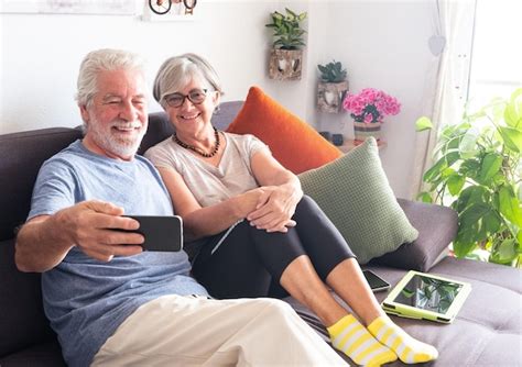 Premium Photo Smiling Senior Couple Taking Selfie While Sitting On