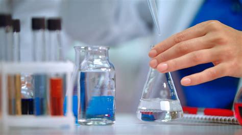chemical reaction in lab flask close up of female chemist hands doing