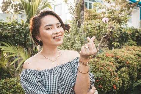 A Beautiful Short Haired Asian Woman Wearing An Off Shoulder Top Gives