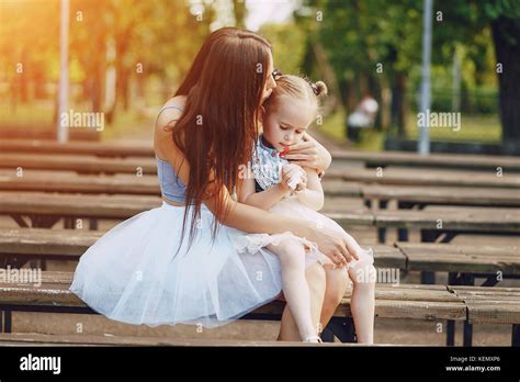 A Beautiful Young Slim And Long Haired Mom Sitting In The Park With Her