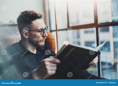 Attractive Stylish Businessman Reading Black Book While Sitting In
