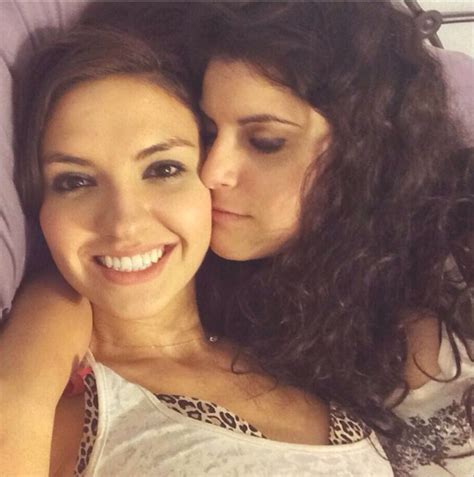 Two Women Laying In Bed With Their Arms Around Each Other And Smiling