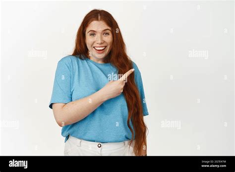 Excited Ginger Girl With Hopeful Smile Pointing Finger At Upper Right
