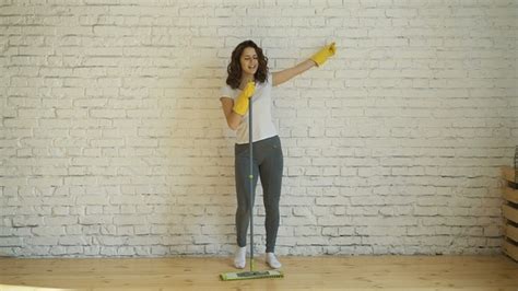 Beautiful Young Woman In Protective Gloves Is Singing Using A Mop And