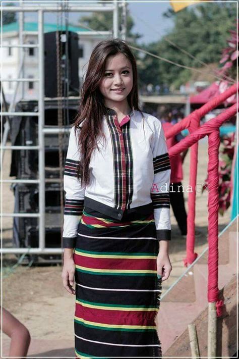 A Woman Standing In Front Of A Stage Wearing A Striped Skirt And White