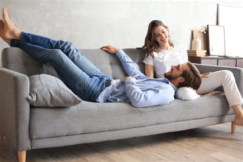 Joven Pareja Amorosa En El Sofá De Casa Viendo La Televisión Y Riendo