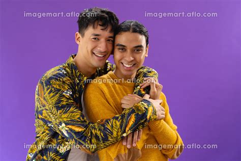 Portrait Of Happy Biracial Couple Embracing And Smiling On Purple