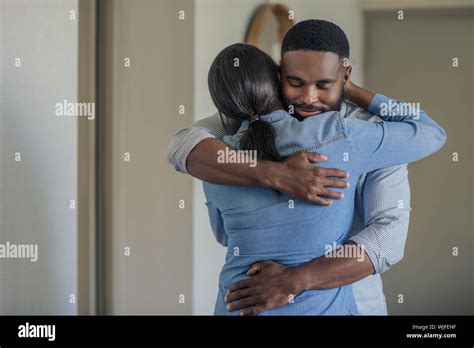 Affectionate Young African American Man Hugging His Wife At Home Stock
