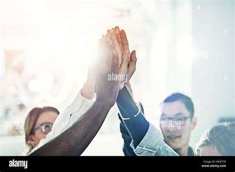 Diverse Group Of Coworkers High Fiving Each Other While Standing In A