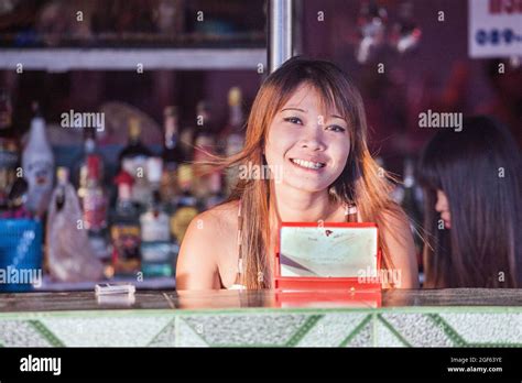 Pretty Thai Bar Girl Sits Smiling At Counter With Vanity Mirror In