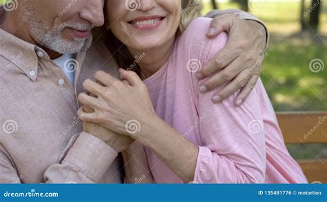 Loving Senior Couple Embracing In Park Comfortable Retirement Secure