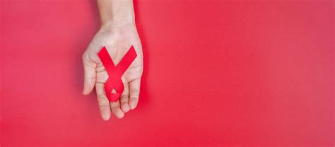 Hand Holding Red Ribbon For Supporting People Living And Illness