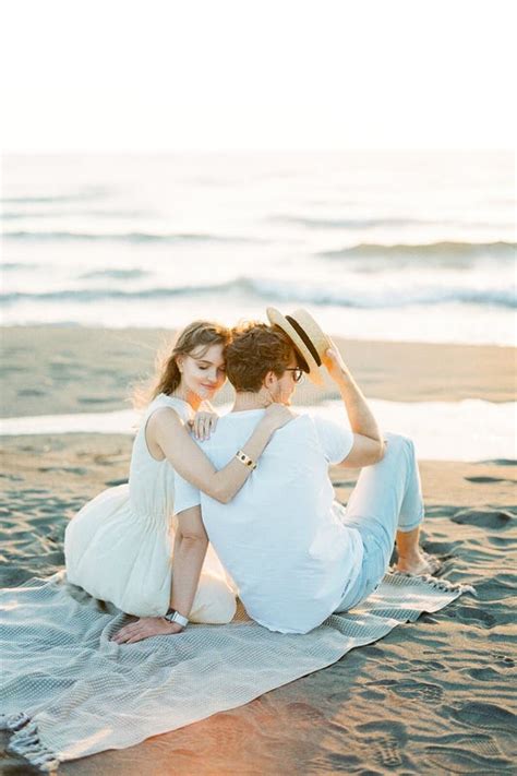 Woman Hugging Man Shoulder While Sitting On The Beach Stock Image
