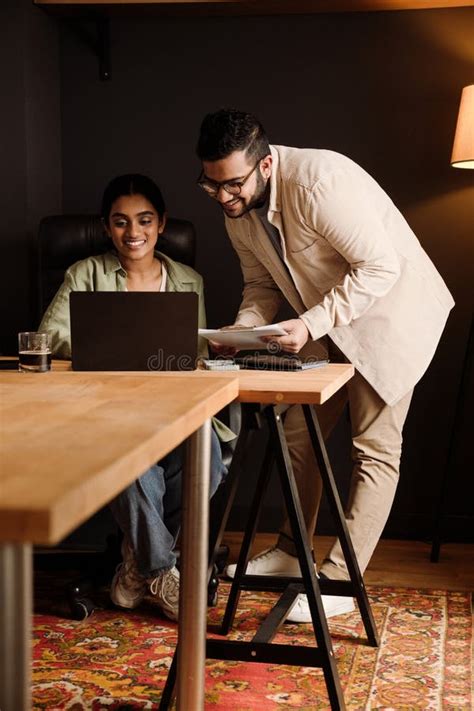 Two Indian Coworkers Using Laptop While Working Together In Office