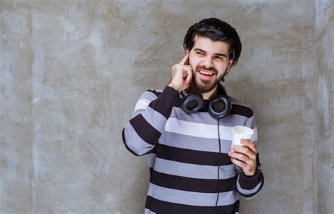 Premium Photo Man With Headphones Holding A White Water Cup