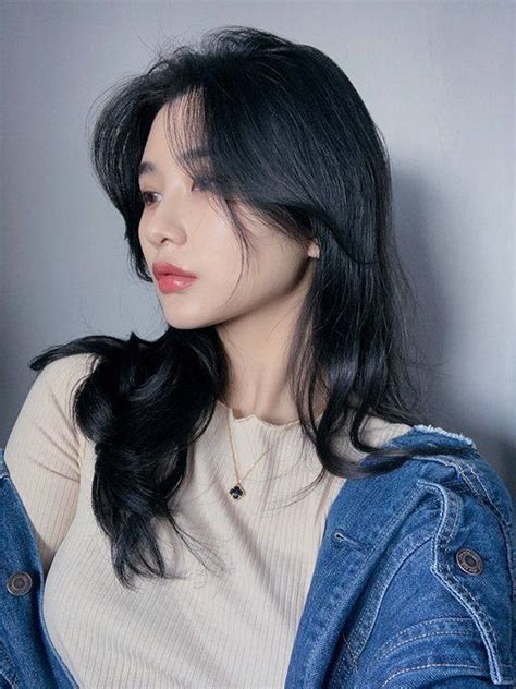 A Woman With Long Black Hair Is Wearing A Jean Jacket And Looking Off