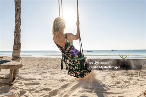 Young Woman Having Fun Swinging On The Beach At Sunrise High Res Stock