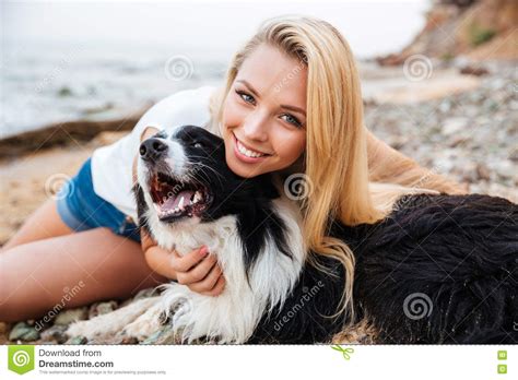 Femme Gaie Reposant Et étreignant Son Chien Sur La Plage Image Stock
