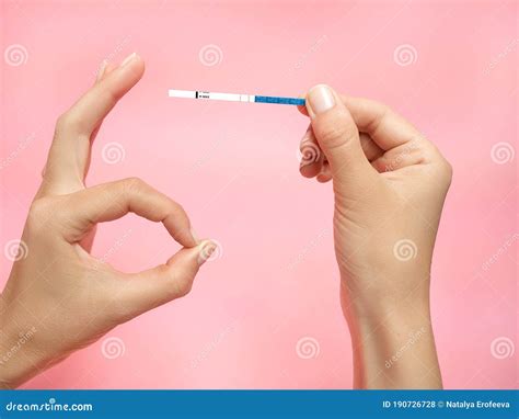 Female Hand Holding Positive Pregnancy Test And Showing Gesture Ok