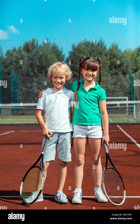 Curly Blonde Brother Standing Near Sister Standing On Tennis Court