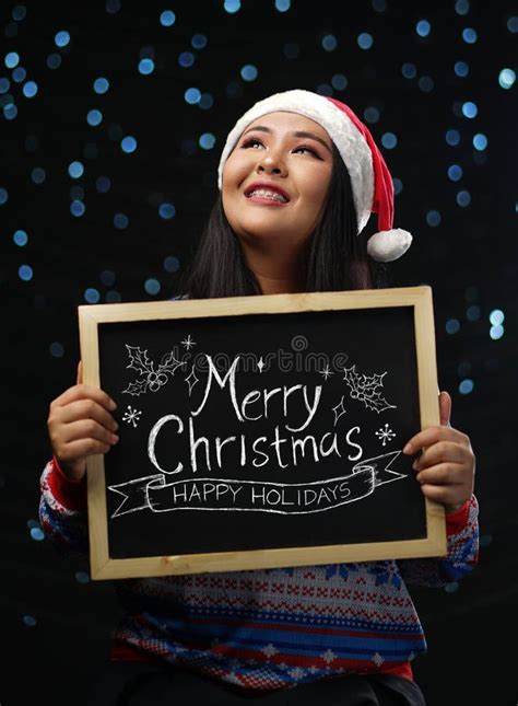 Asian Girl Wearing Christmas Sweater And Santa Hat Holding Small Stock