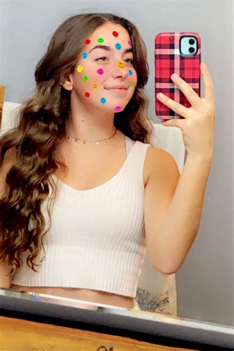 A Girl With Colorful Confetti On Her Face Taking A Selfie In Front Of A