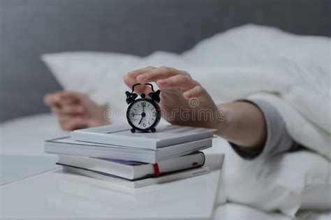 Female Hand Turns Off The Ringing Alarm Clock Early In The Morning