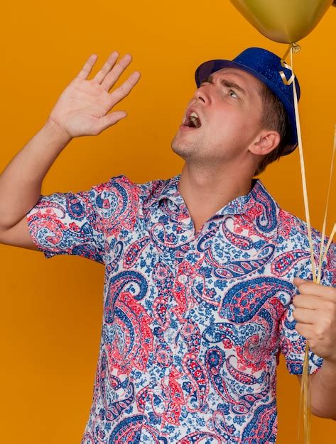 Free Photo Unpleased Young Party Guy Wearing Blue Hat Holding