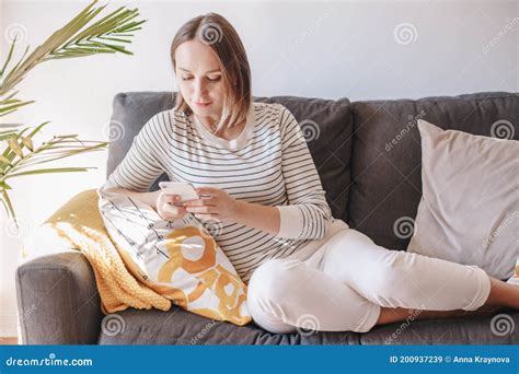 Young Woman Sitting On Couch And Texting Talking At Social Media On