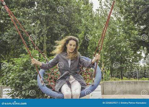 The Girl Swings On A Swing In The Park On A Sunny Day Stock Image