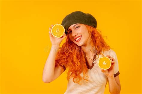 Caucasian Red Haired Woman Holding Oranges While Standing In Front Of A