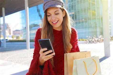 سيدة أنيقة تتسوق عبر الإنترنت بهاتفها الذكي أثناء الاسترخاء على مقعد في