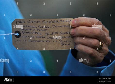 A Former Evacuee Shows A Handwritten Label With Information About Her