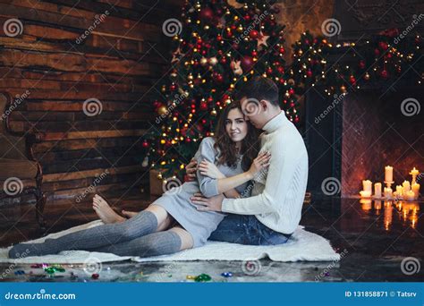Romantic Couple Hugging Near Christmas Tree And Fireplace At Home In