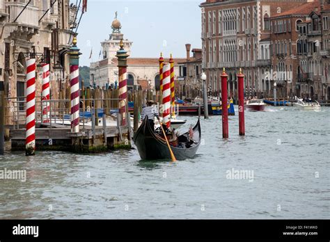 Gondolas On The Grand Canal In Venice By Striped Mooring Poles Stock