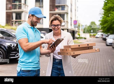 Professional Delivery Man Wearing Blue Uniform Delivers Pizza To A