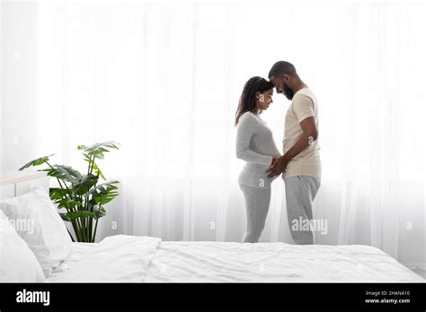 Cheerful Young Black Man And Pregnant Wife Enjoy Tender Moment In