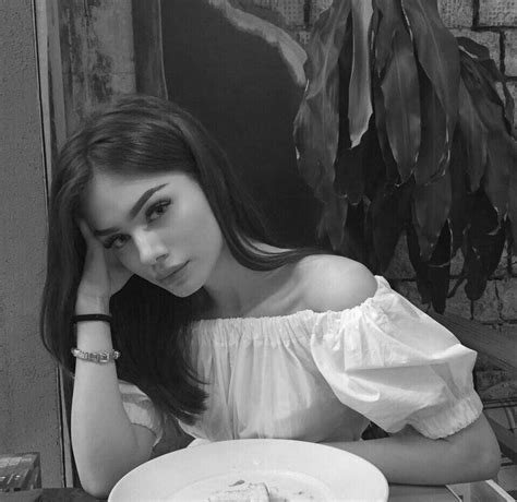 A Black And White Photo Of A Woman Sitting At A Table