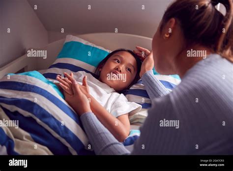 Asian Mother Talking To Daughter In Top Bunk Bed Before She Goes To