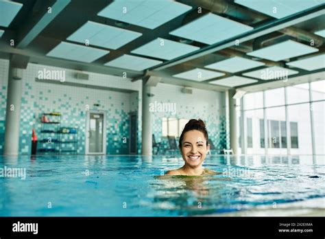 A Young Brunette Woman In A Swimsuit Smiles While Submerged In An