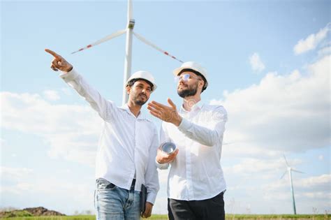 Two Engineers Discussing Against Turbines On Wind Turbine Farm Stock