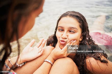 Two Young Spanish Women Playing And Making Mockery Faces In Beach Stock
