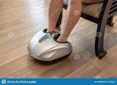 Man Relaxing While Having A Foot Massage On A Machine At Home Stock